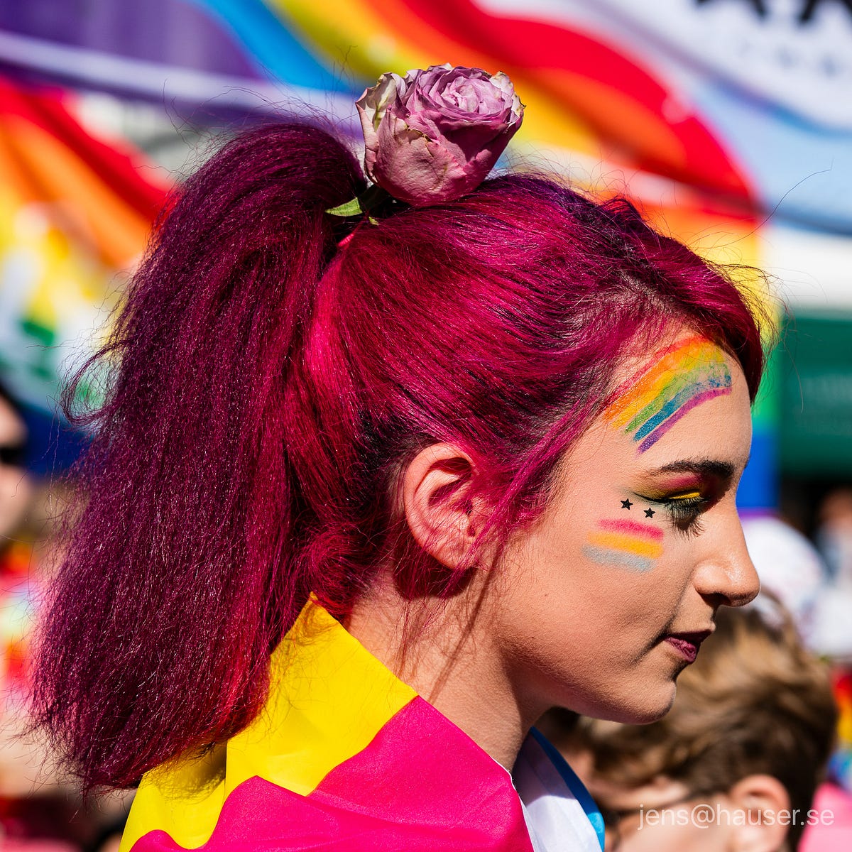 Vibrant burgundy hair and rainbow face paint capture the joyful spirit ...