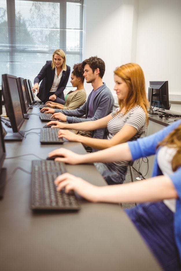 Premium Photo | Computer teacher helping a pretty student in her class ...