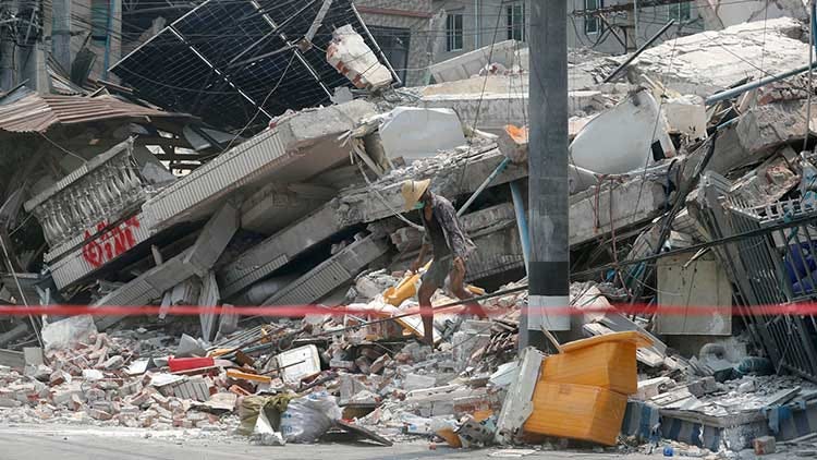 "A man walks through the rubble of collapsed buildings after an ...